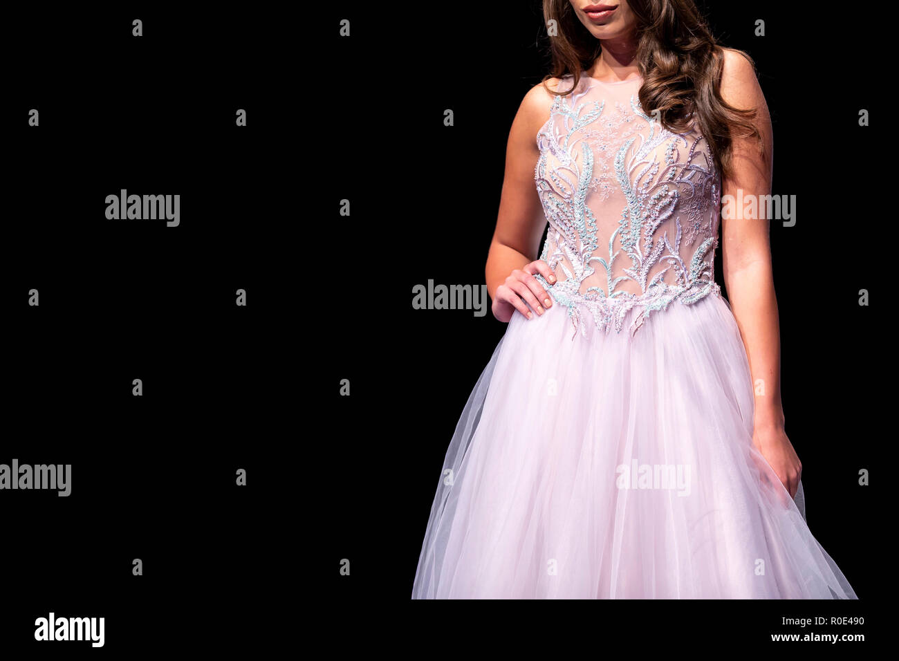 Female model walks the runway in pink dress isolated on a black ...
