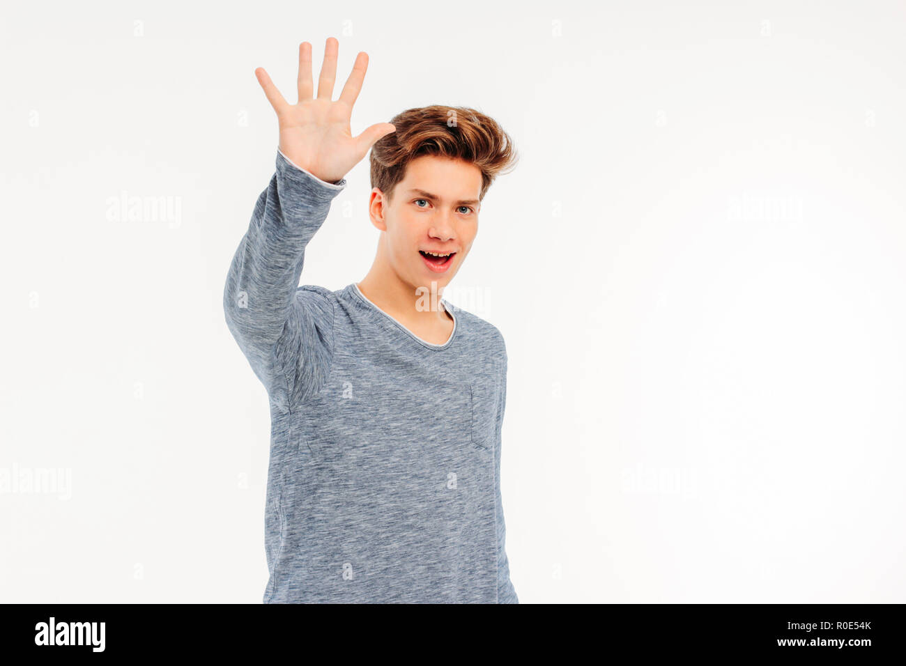 Smiling young guy welcomes saying goodbye to hand on white background ...