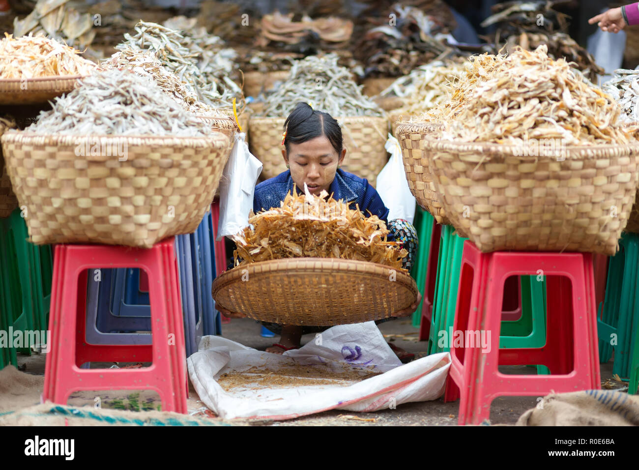 MANDALAY,MYANMAR,JANUARY 17, 2015: A seller is sieving the dry fish in ...