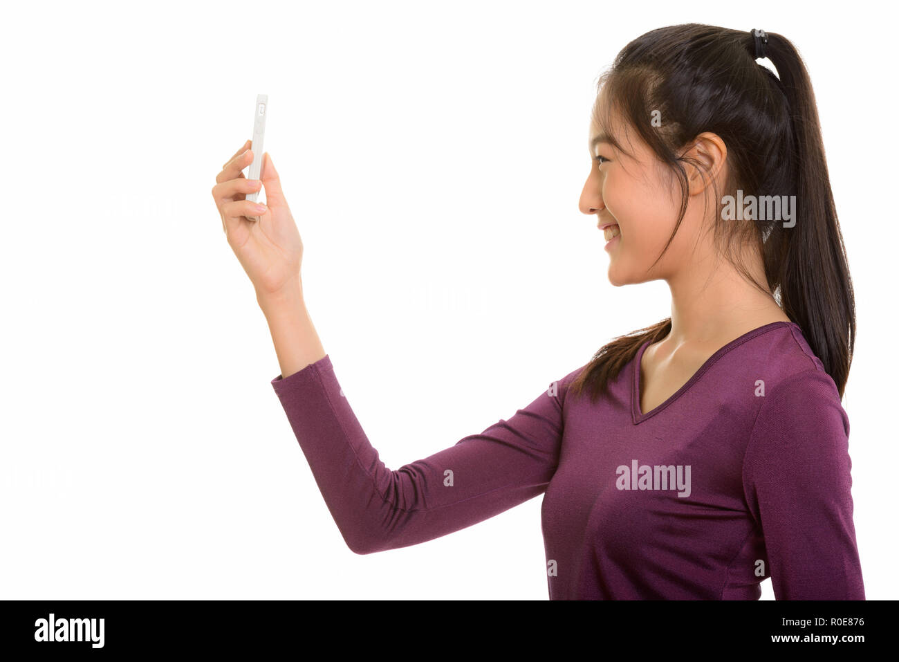 Profile view of young happy Asian teenage girl smiling while tak Stock ...