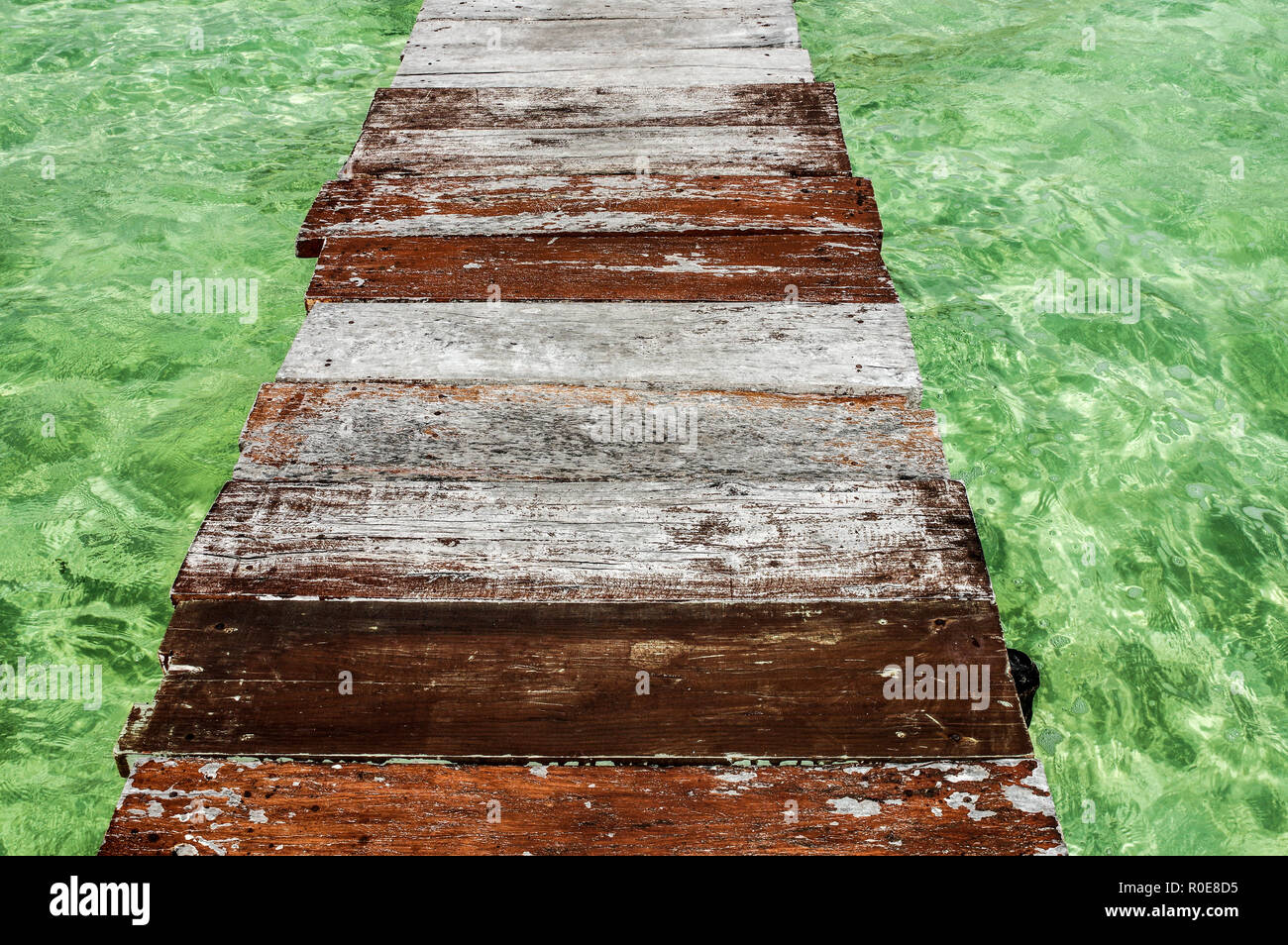 Old rustic boardwalk over the crystal-clear waters of a lagoon near ...