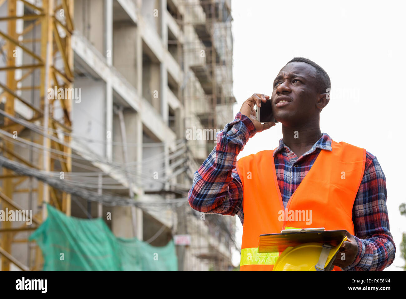 Thoughtful young black African man construction worker talking o Stock ...