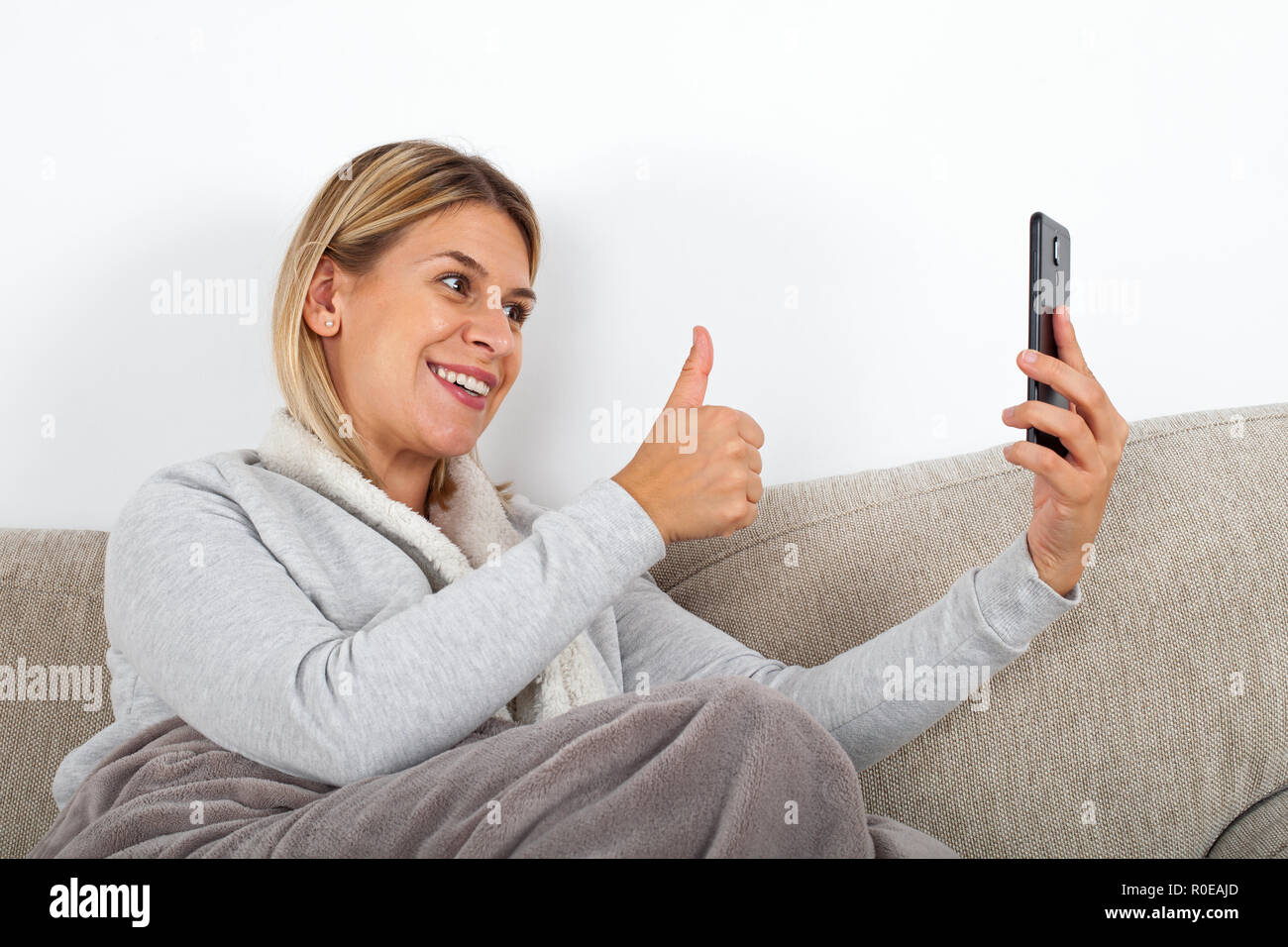 Attractive young woman talking with friend on facetime, showing thumbs ...