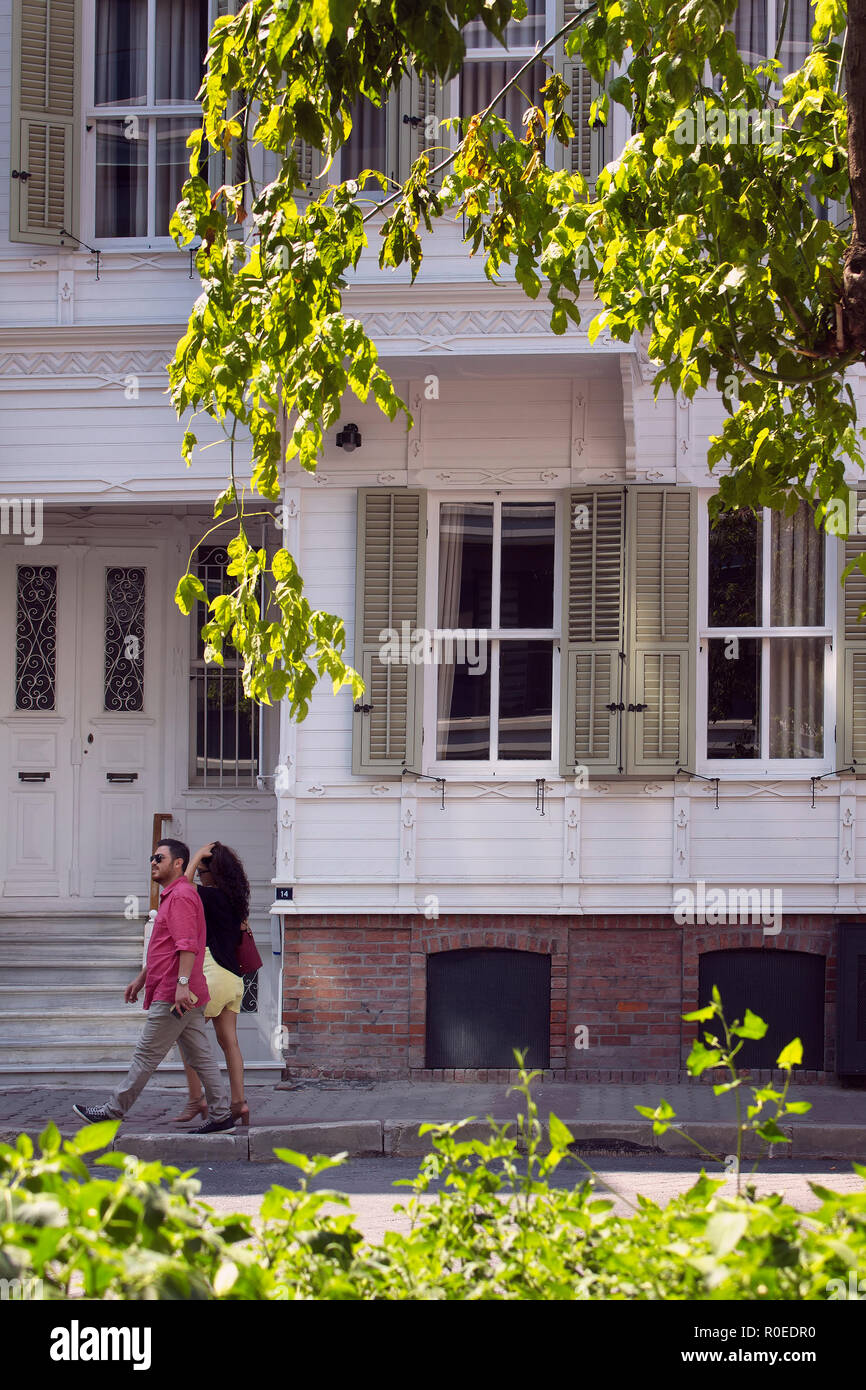Couple walks by a white, wooden, historical house in Moda neighborhood ...