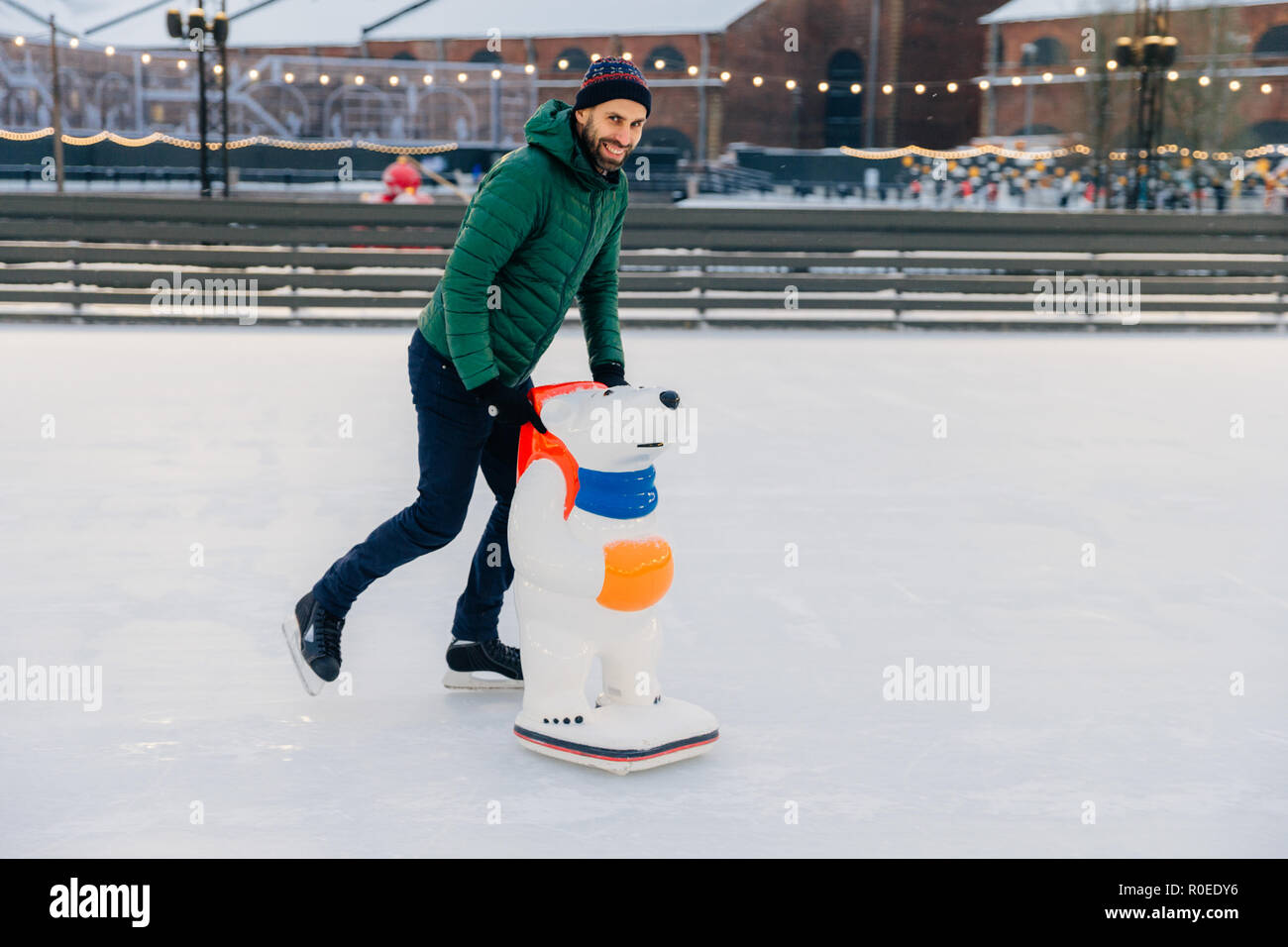 Portrait of glad handsome middle aged male skates on ice rink with ...