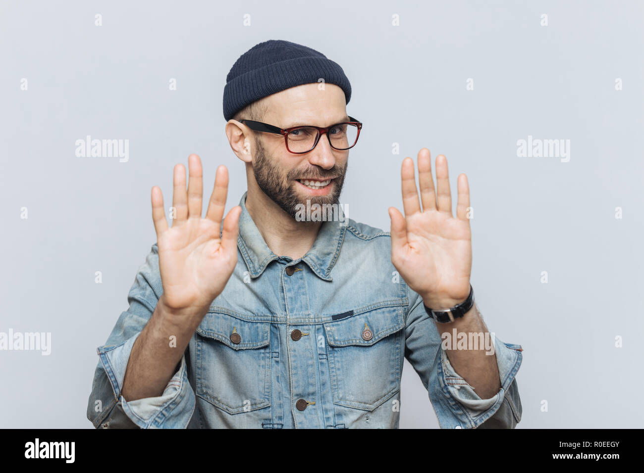 Don`t bother me! Cheerful male with pleasant appearance shows stop sign ...
