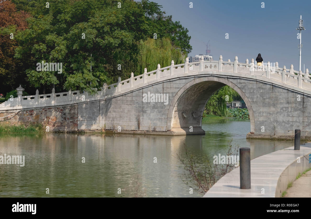 White stone footbridge in an Chinese garden lacated among the modern ...