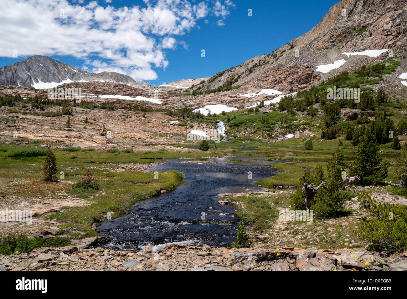 Beautiful meadow with a stream, waterfall and summer snow in California ...