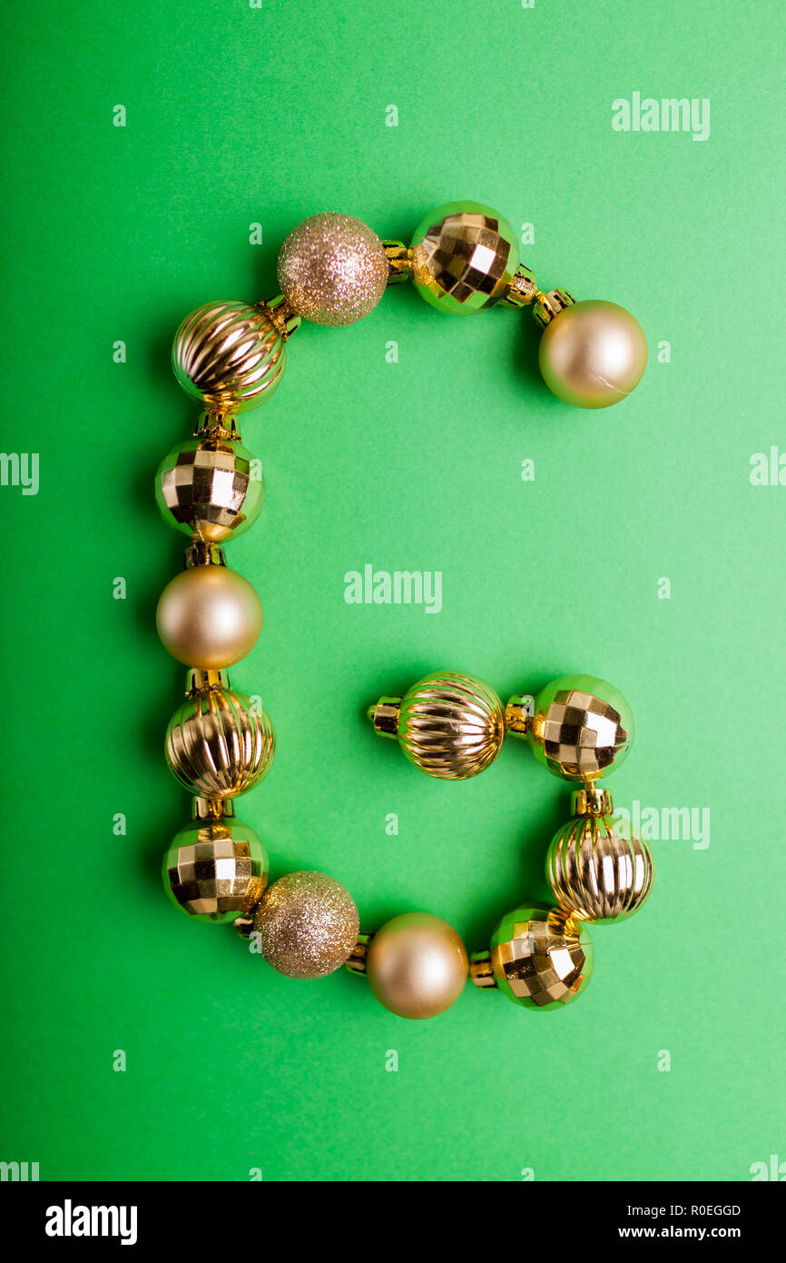 Letter G made of Christmas toys on green background. ABC made of golden ...