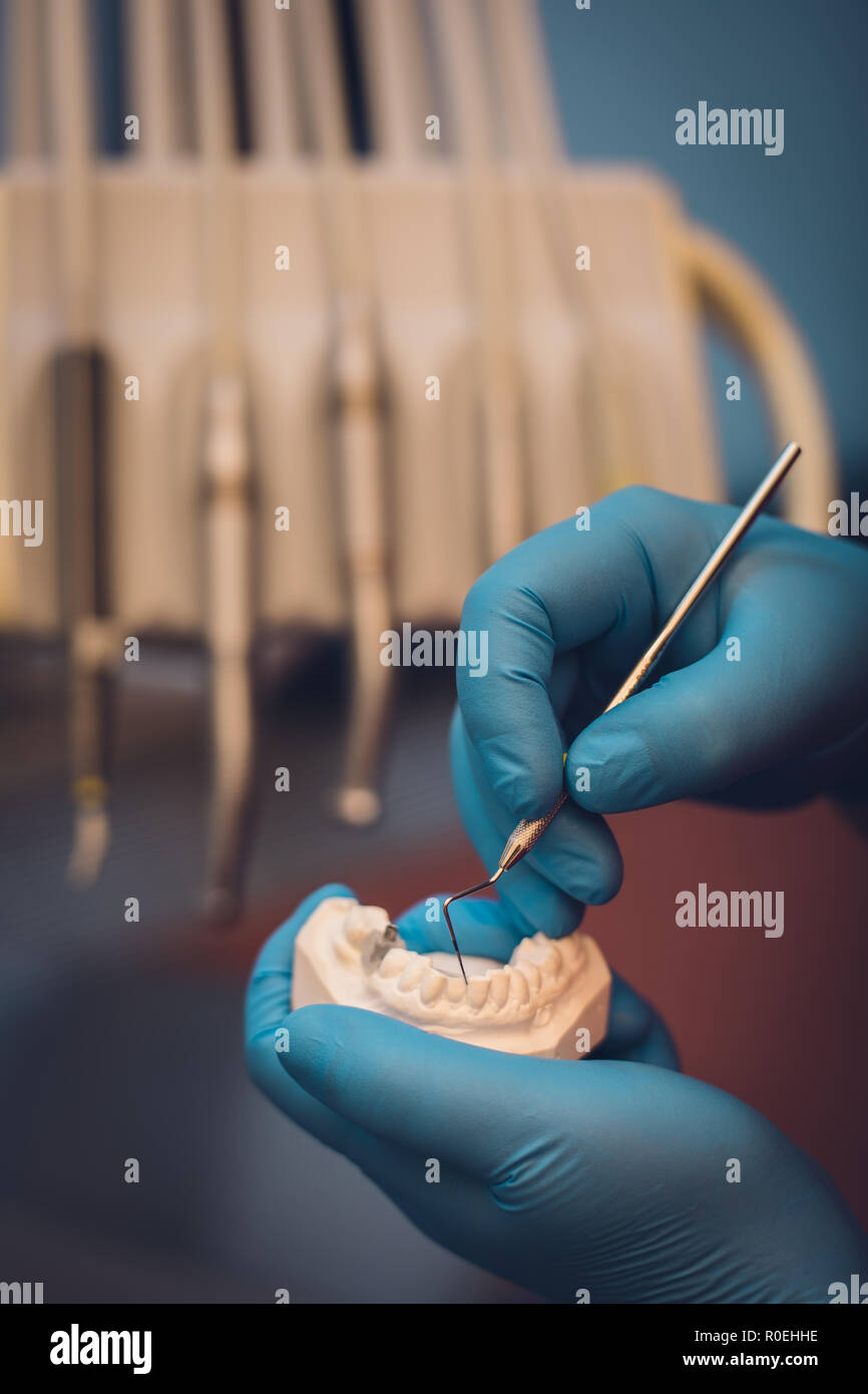 Detailed close up of dental instrument working on a denture or teeth ...
