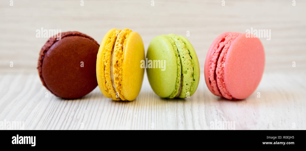 Sweet and colorful macarons on a white wooden background, side view ...