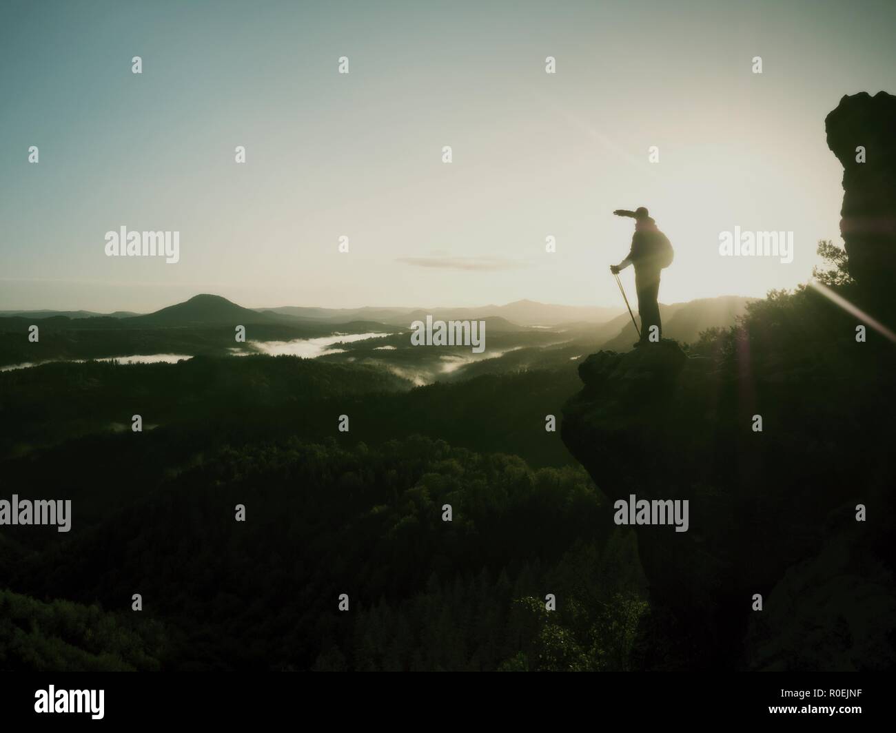 Crazy man at edge. Fearless hiker on cliff above deep hole. Morning or ...