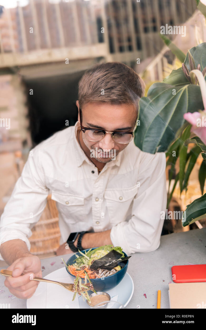 Top view of handsome man wearing glass eating delicious avocado salad ...