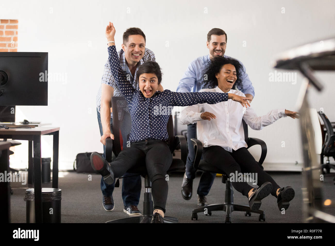Happy multi-ethnic office people having fun riding on chairs Stock ...