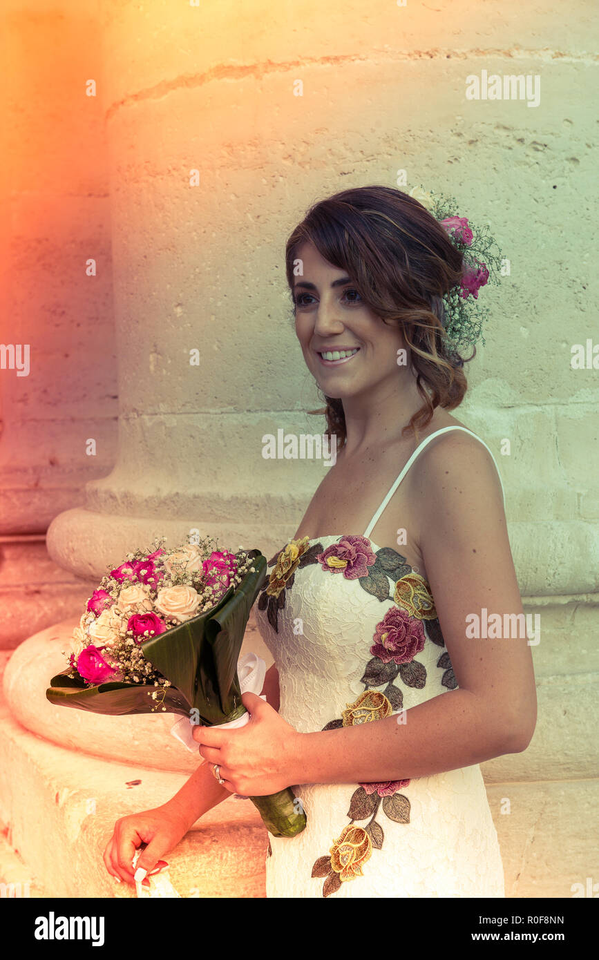 A girl, on the day of her wedding, white dressed, is posing . On the ...