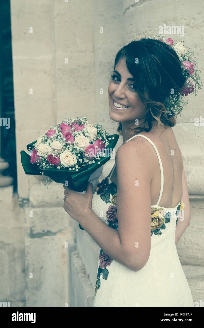 A girl, on the day of her wedding, white dressed, is posing . On the ...