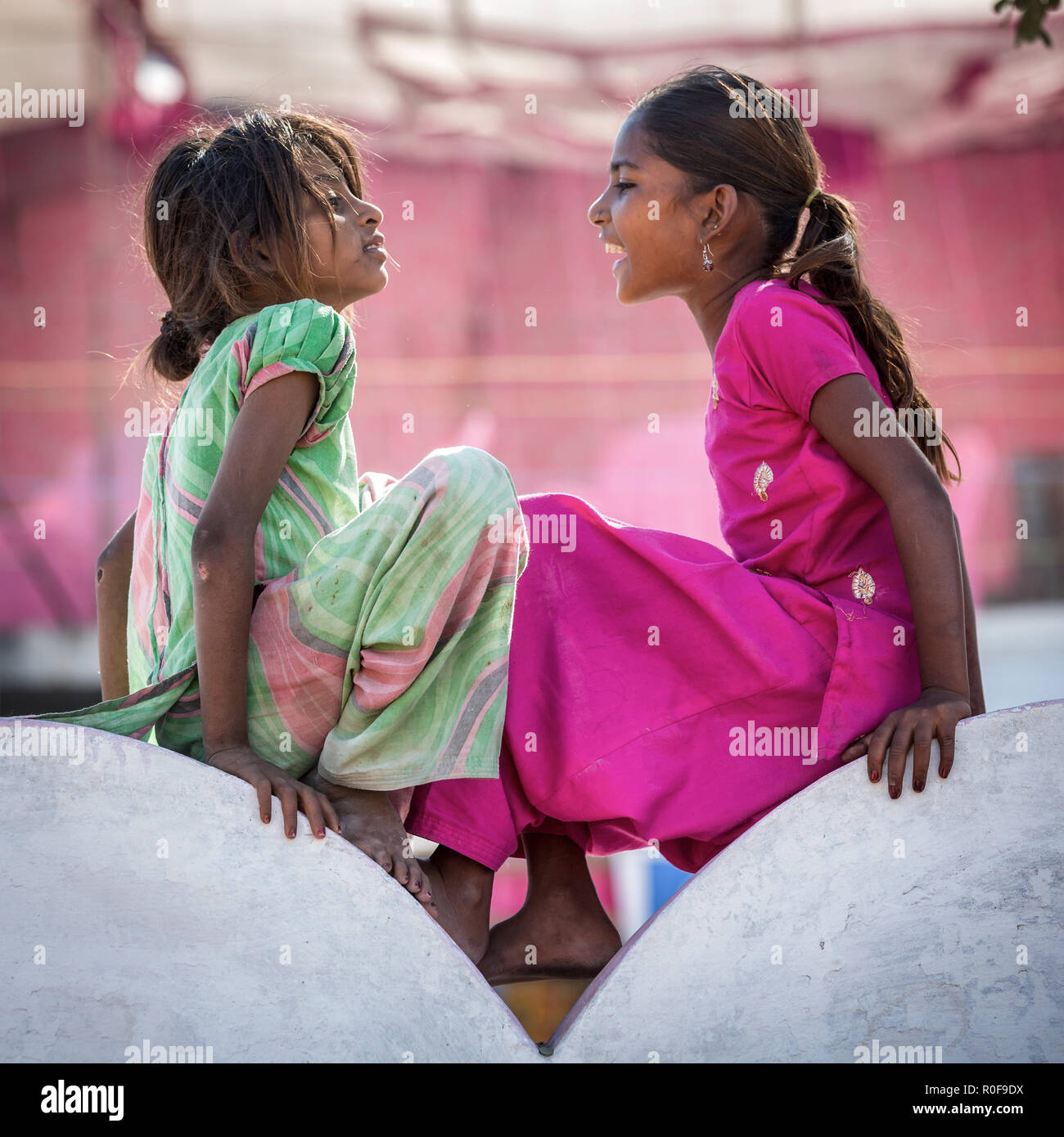 Two poor girls sitting on a wall, portrait, Pushkar, Rajasthan, India ...