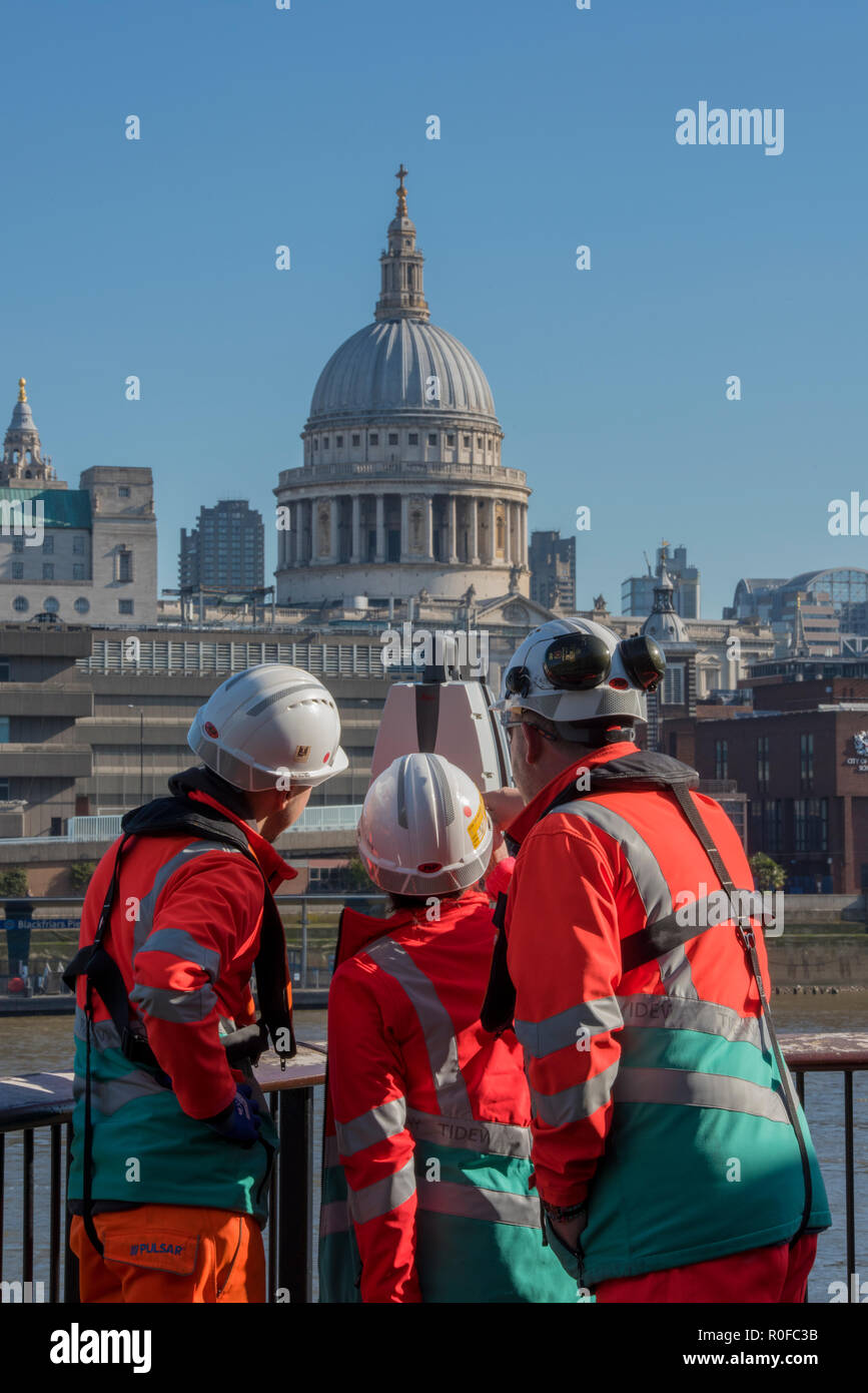 engineers dressed in high visibility clothing and hard hats surveying ...