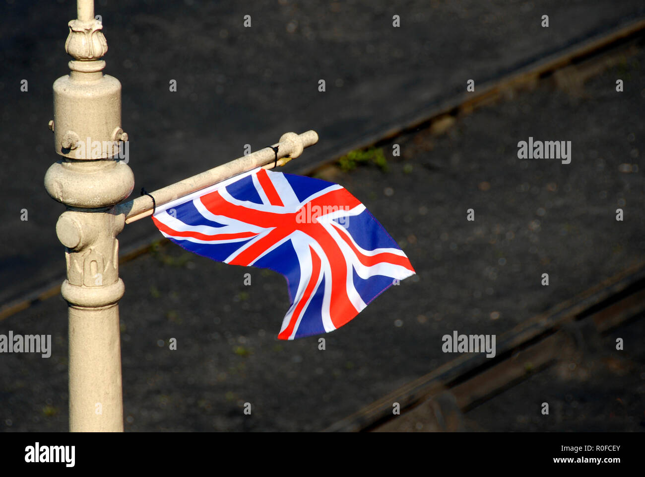 Union flag flying from horizontal strut on pole at railway station ...
