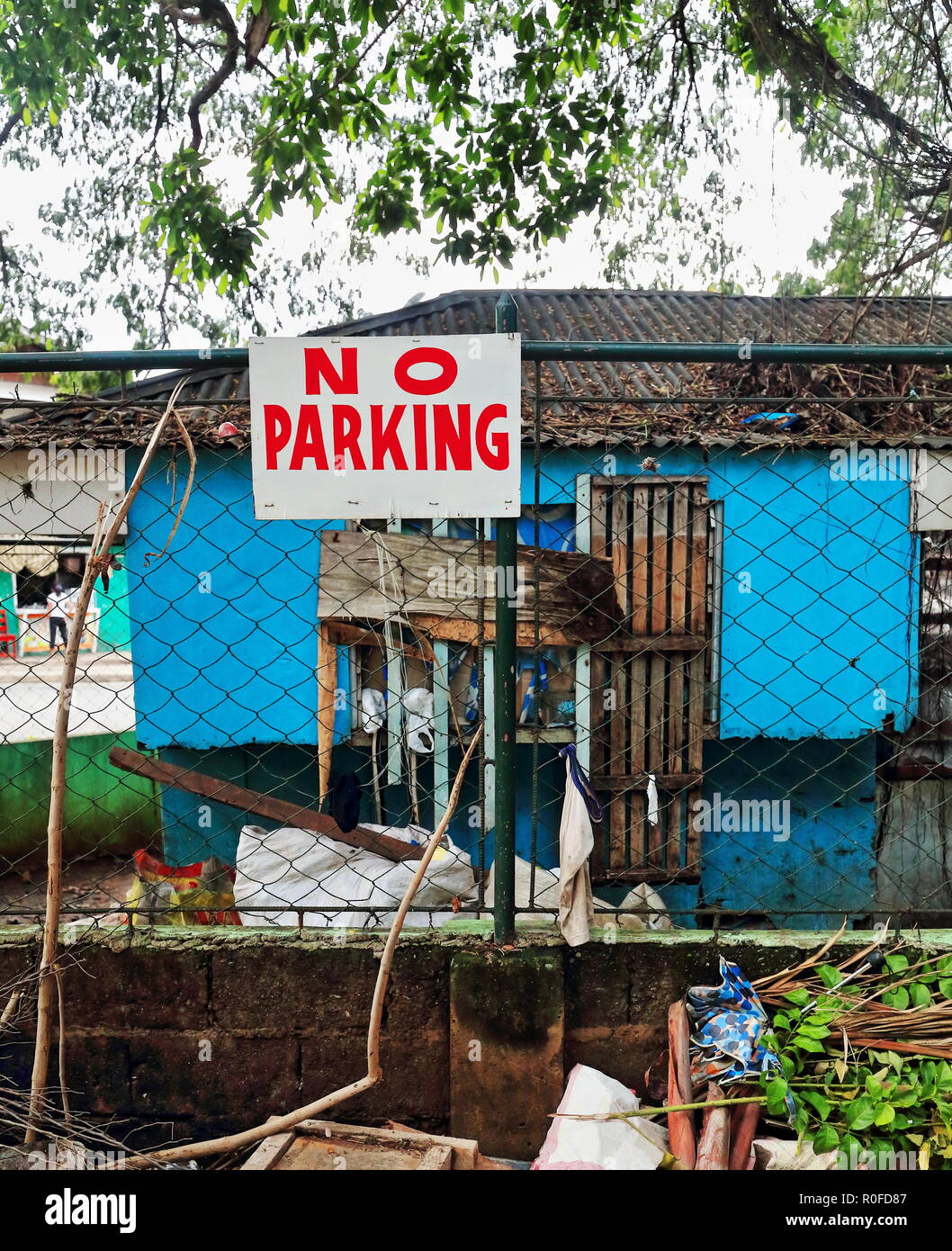 No parking signal stapled on a chain link fence over a backyard brick ...
