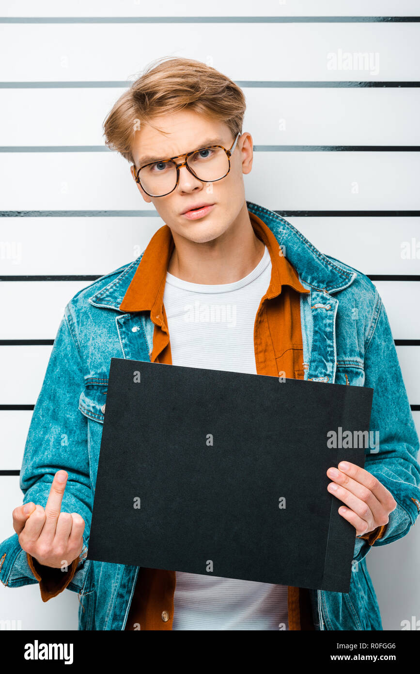 handsome young man holding prison board while standing in front of ...