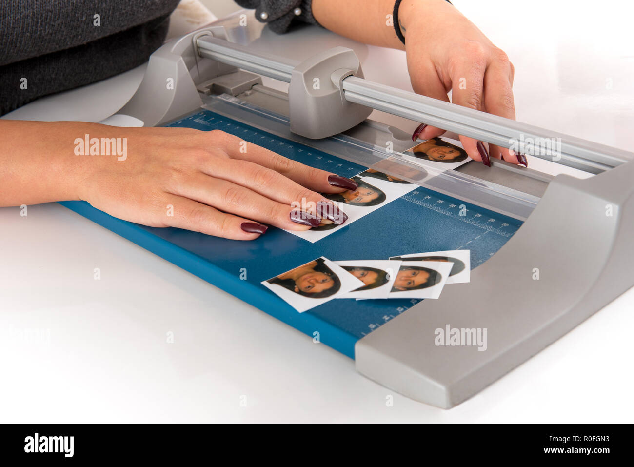 Woman cutting and sizing passport photos in a photographic studio on a ...