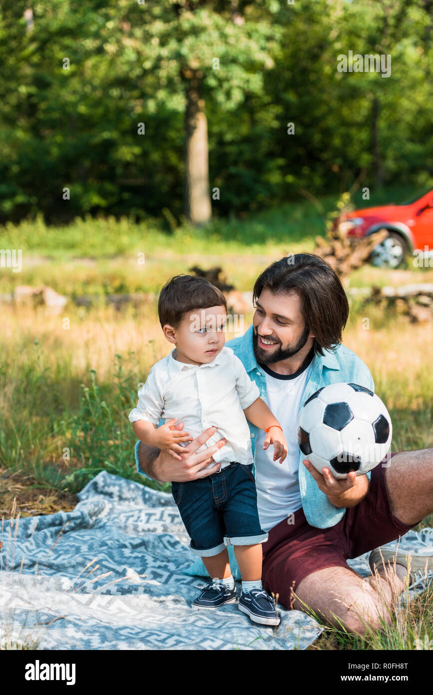 happy father and toddler son playing with football ball at picnic Stock ...