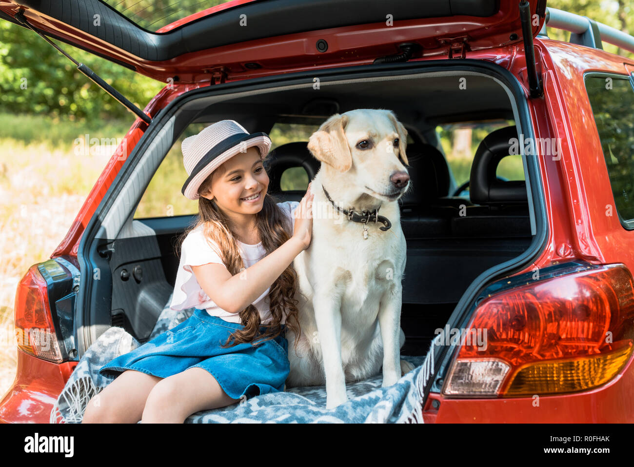 adorable kid hugging dog on car trunk Stock Photo - Alamy