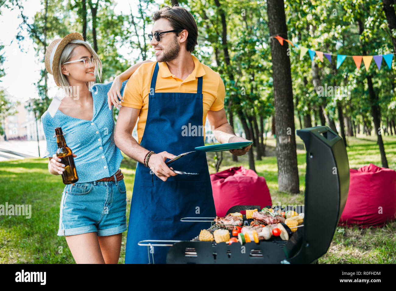 portrait of cheerful couple having barbecue in summer park Stock Photo ...