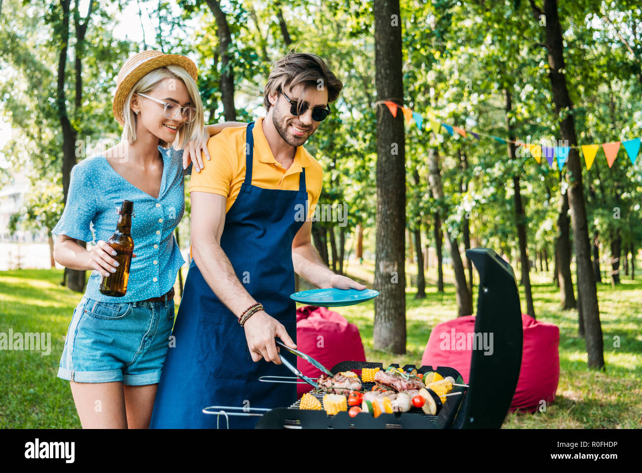 portrait of cheerful couple having barbecue in summer park Stock Photo ...