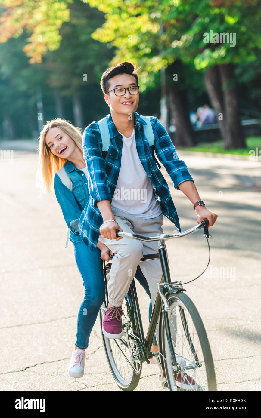happy multiethnic students riding bicycle together on street Stock ...