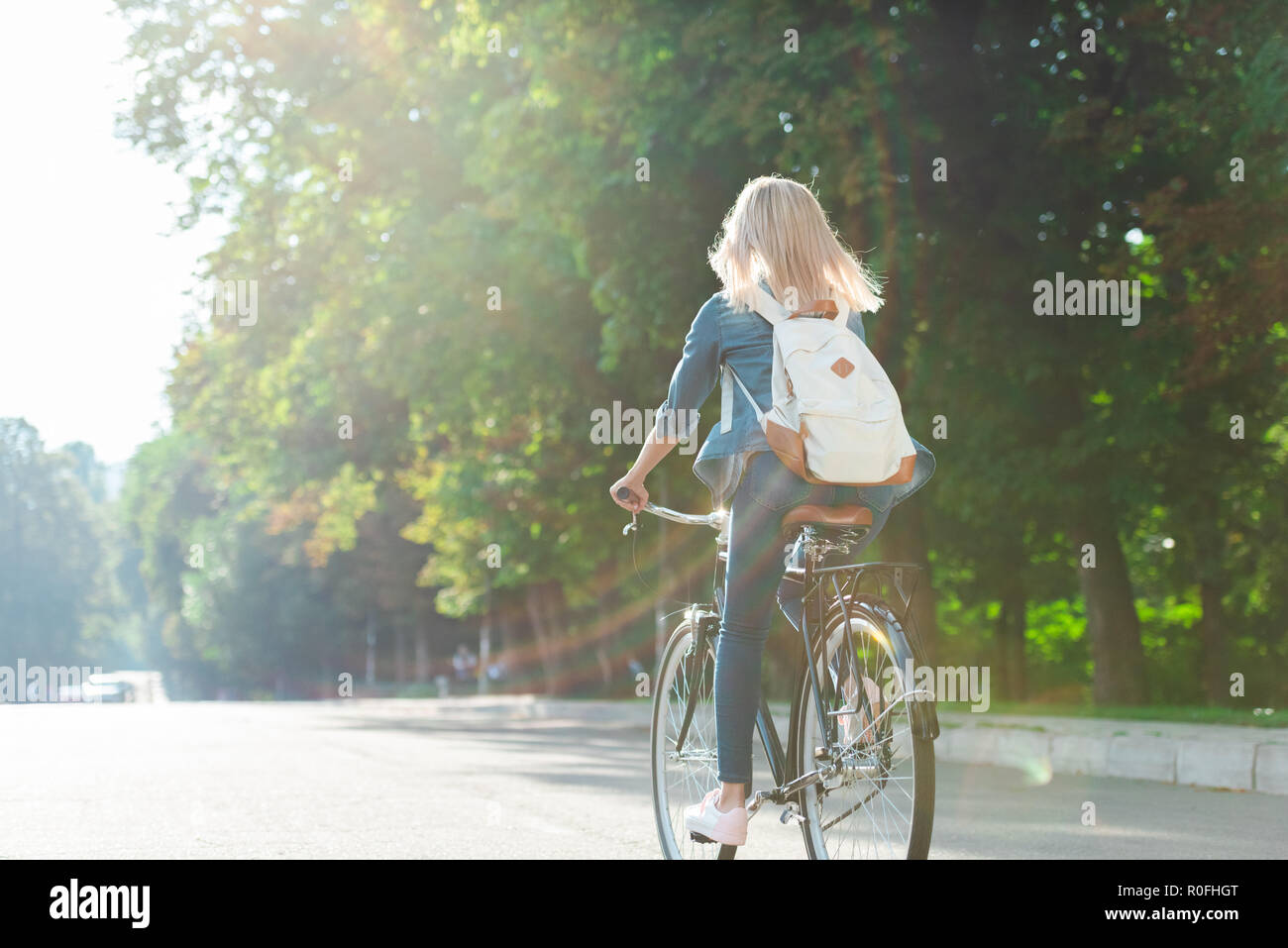 back view of student with backpack riding bicycle on street Stock Photo ...