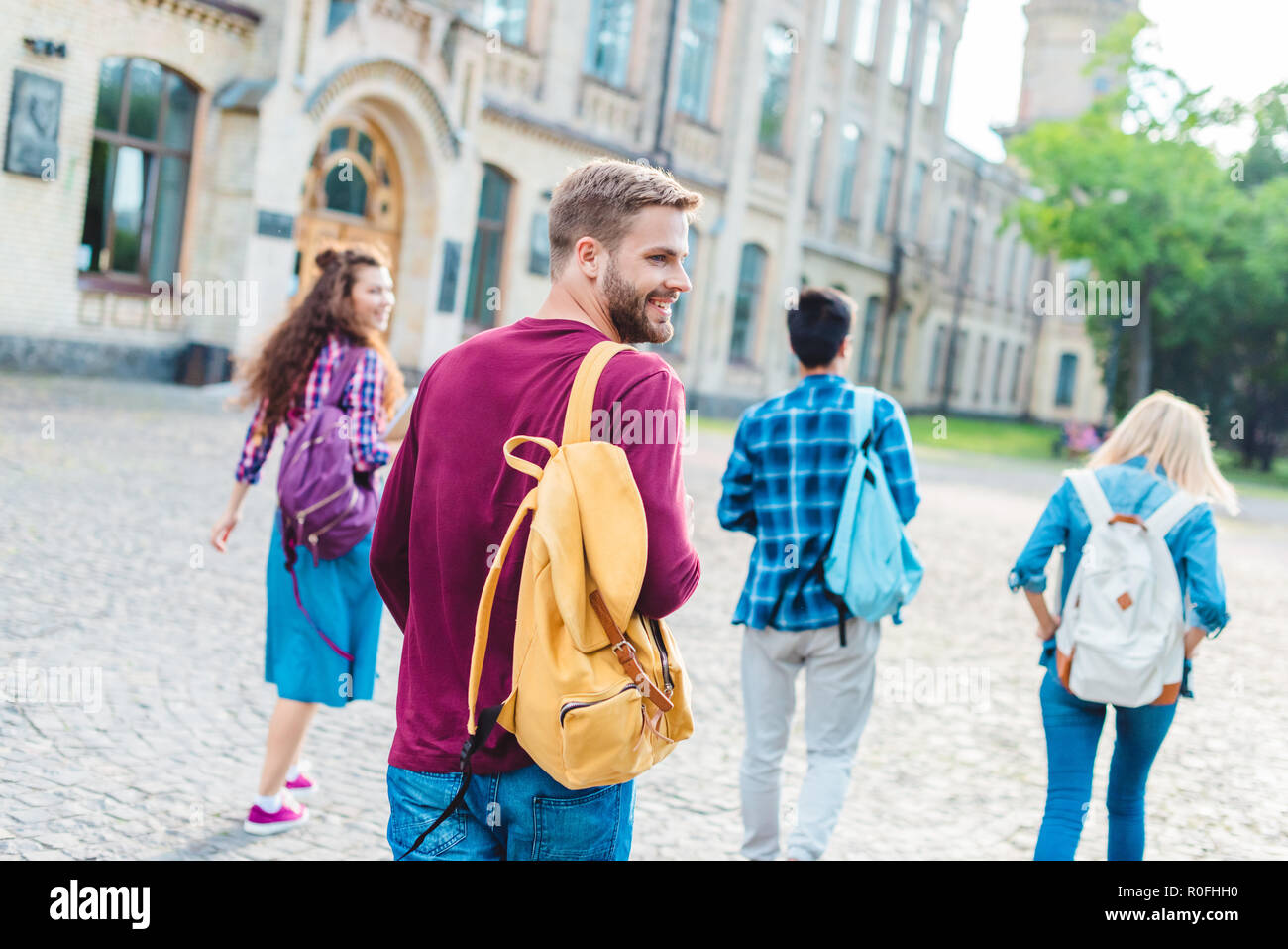back view of students with backpacks walking on street together Stock ...