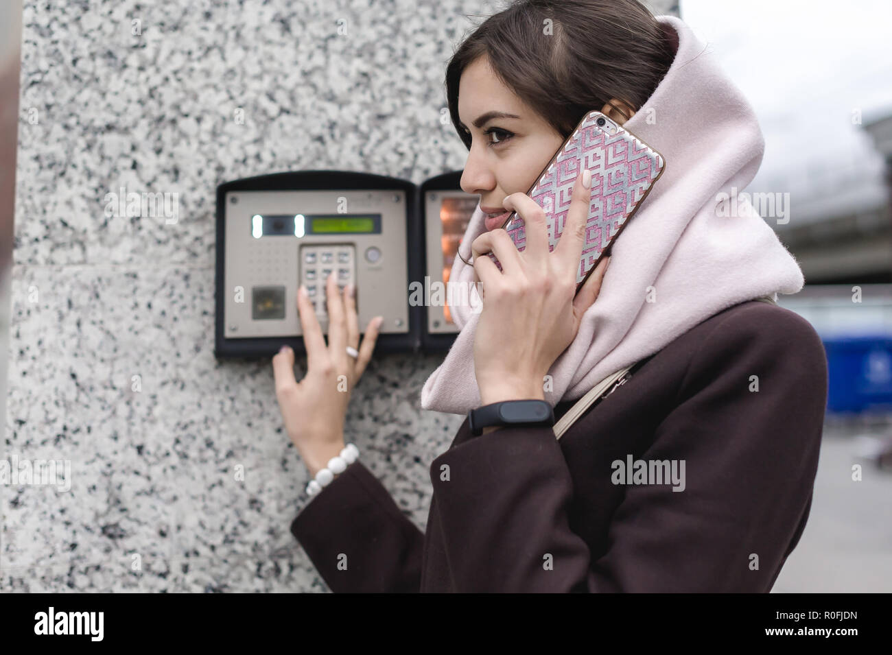 brunette woman calls into the intercom on the street, autumn day in ...
