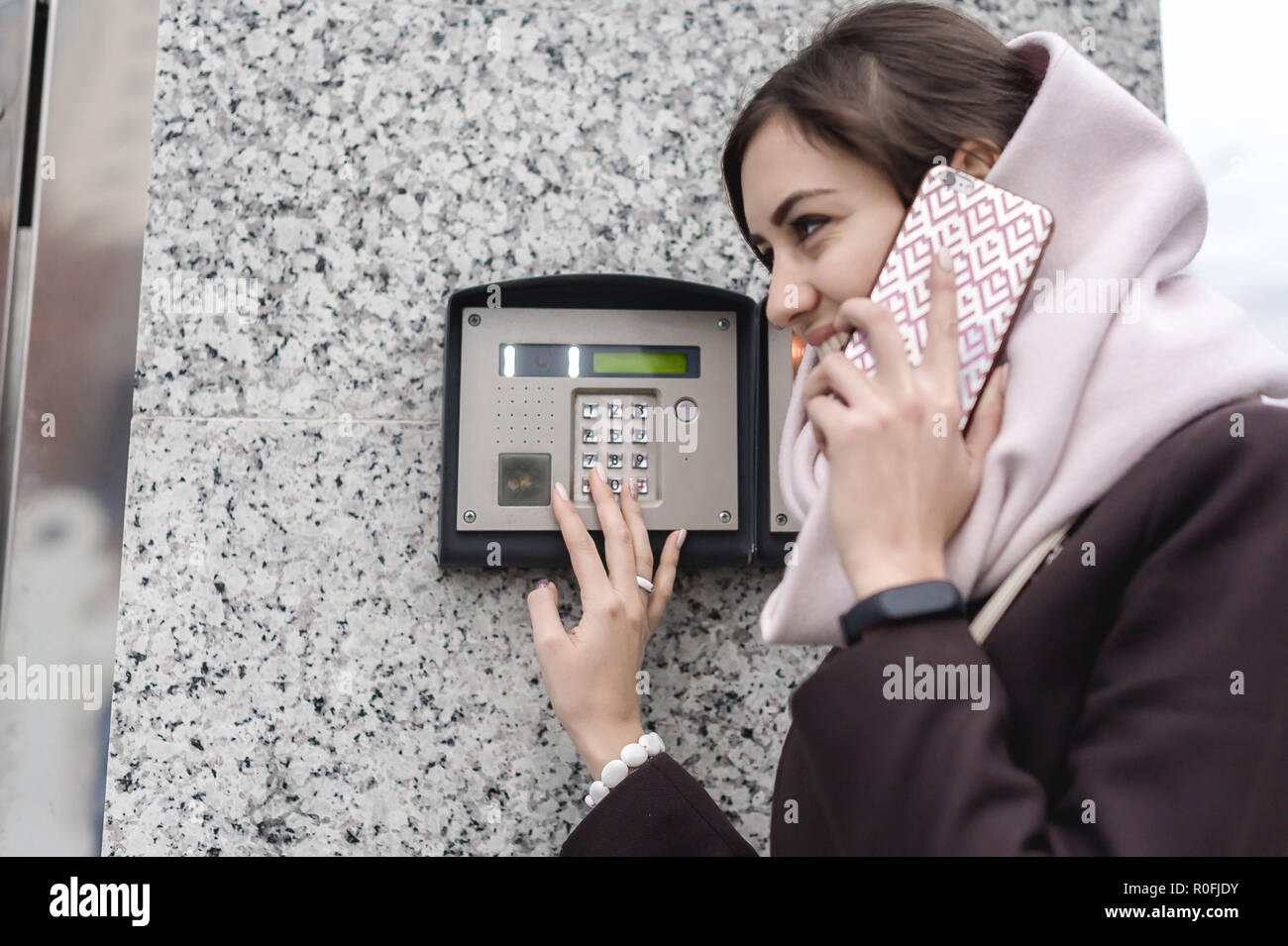 brunette woman calls into the intercom on the street, autumn day in ...
