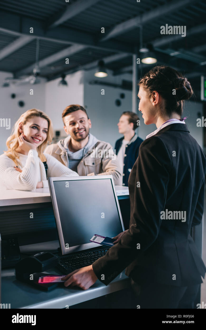 young airport worker checking documents at check-in desk in airport ...