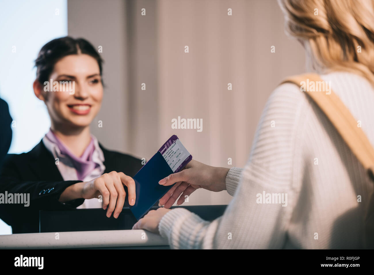 smiling airport worker giving passport with boarding pass to young ...