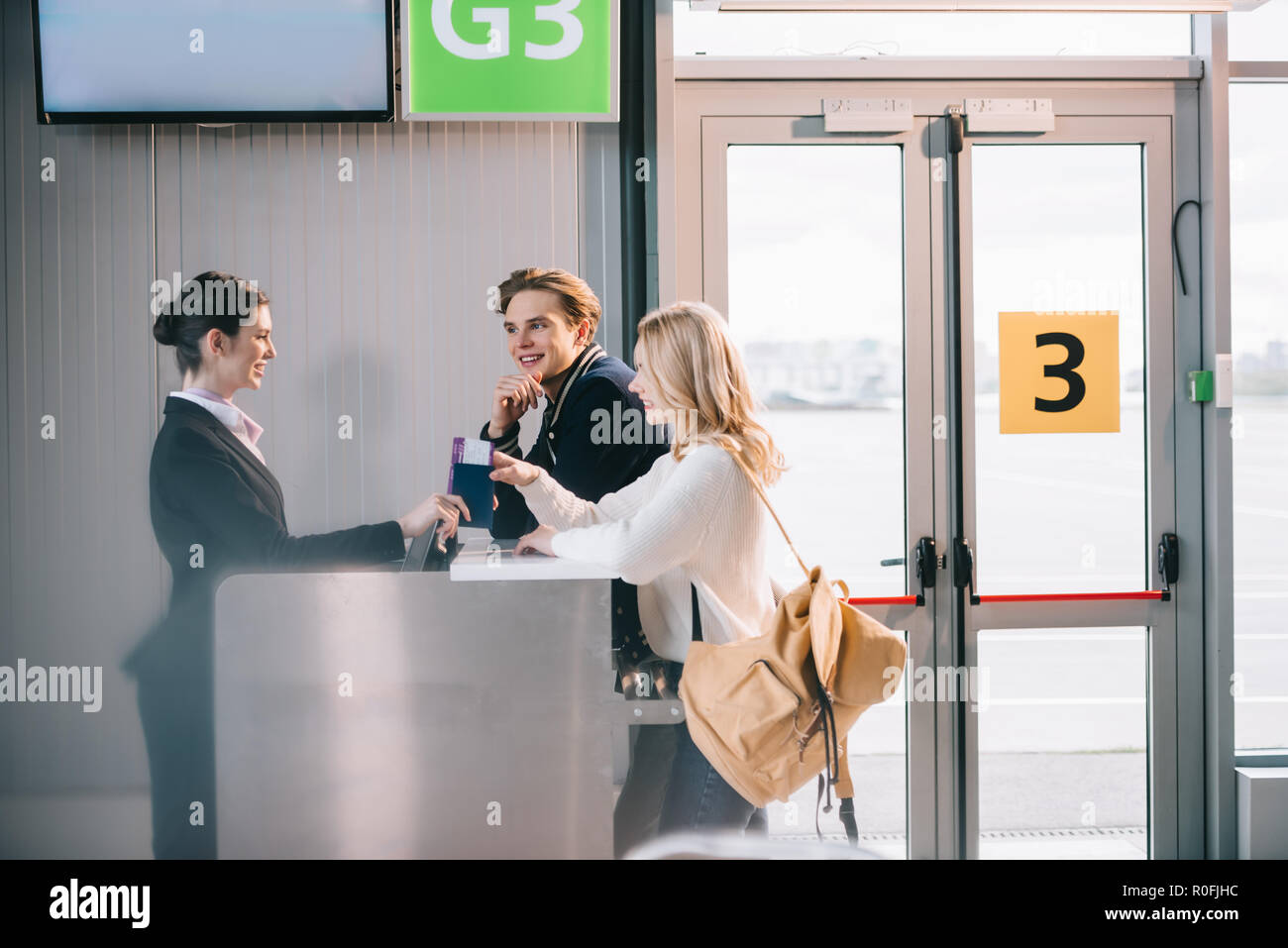 side view of happy young couple at check-in desk in airport Stock Photo ...