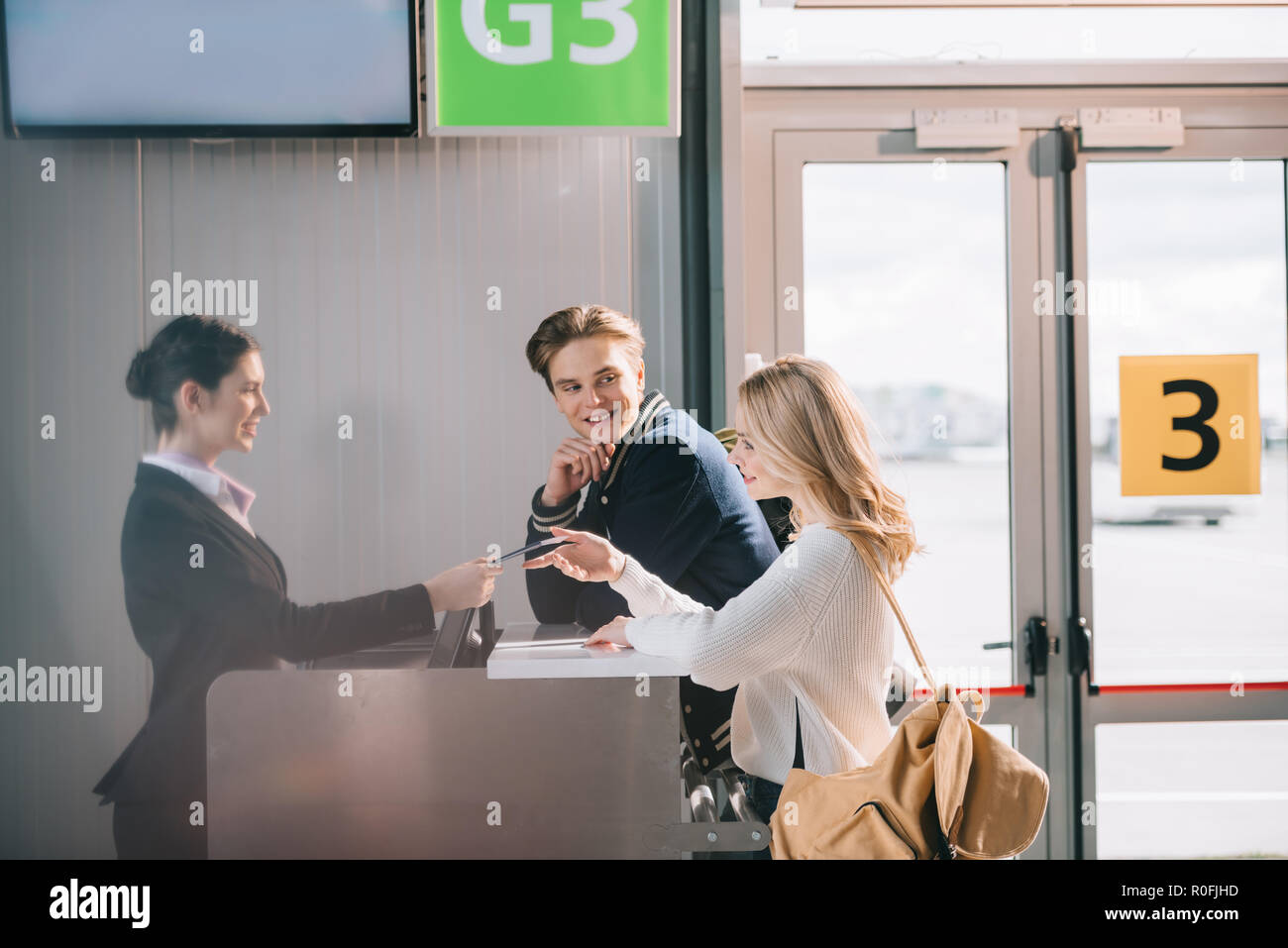 side view of smiling young couple at check-in desk in airport Stock ...