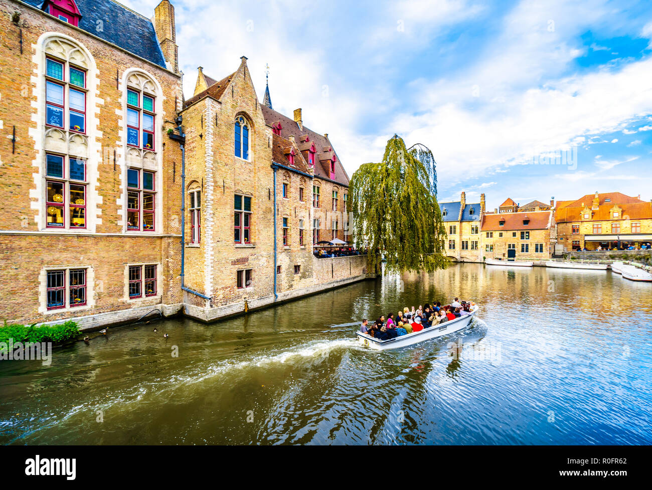 Canal scene with a tourist boat and with surrounding medieval buildings ...