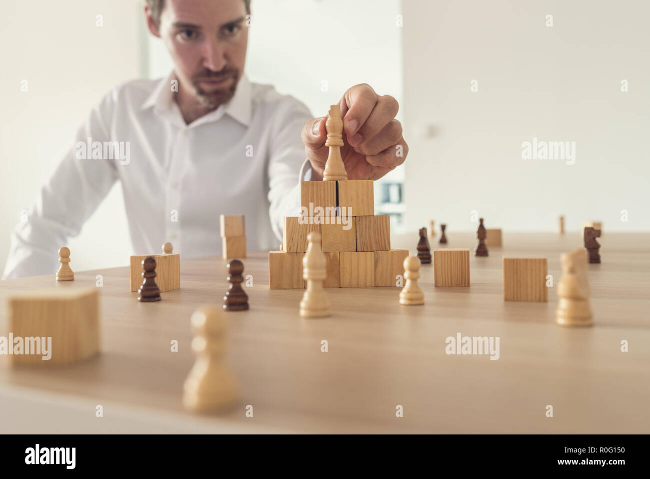 Serious young businessman positioning king chess piece on top of ...