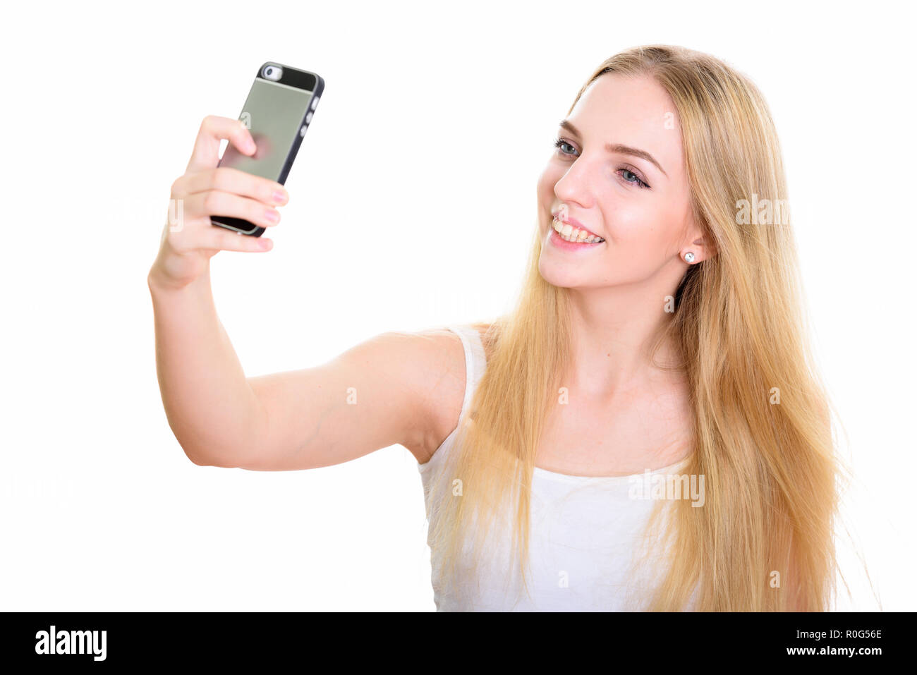 Studio shot of young happy teenage girl smiling while taking sel Stock ...