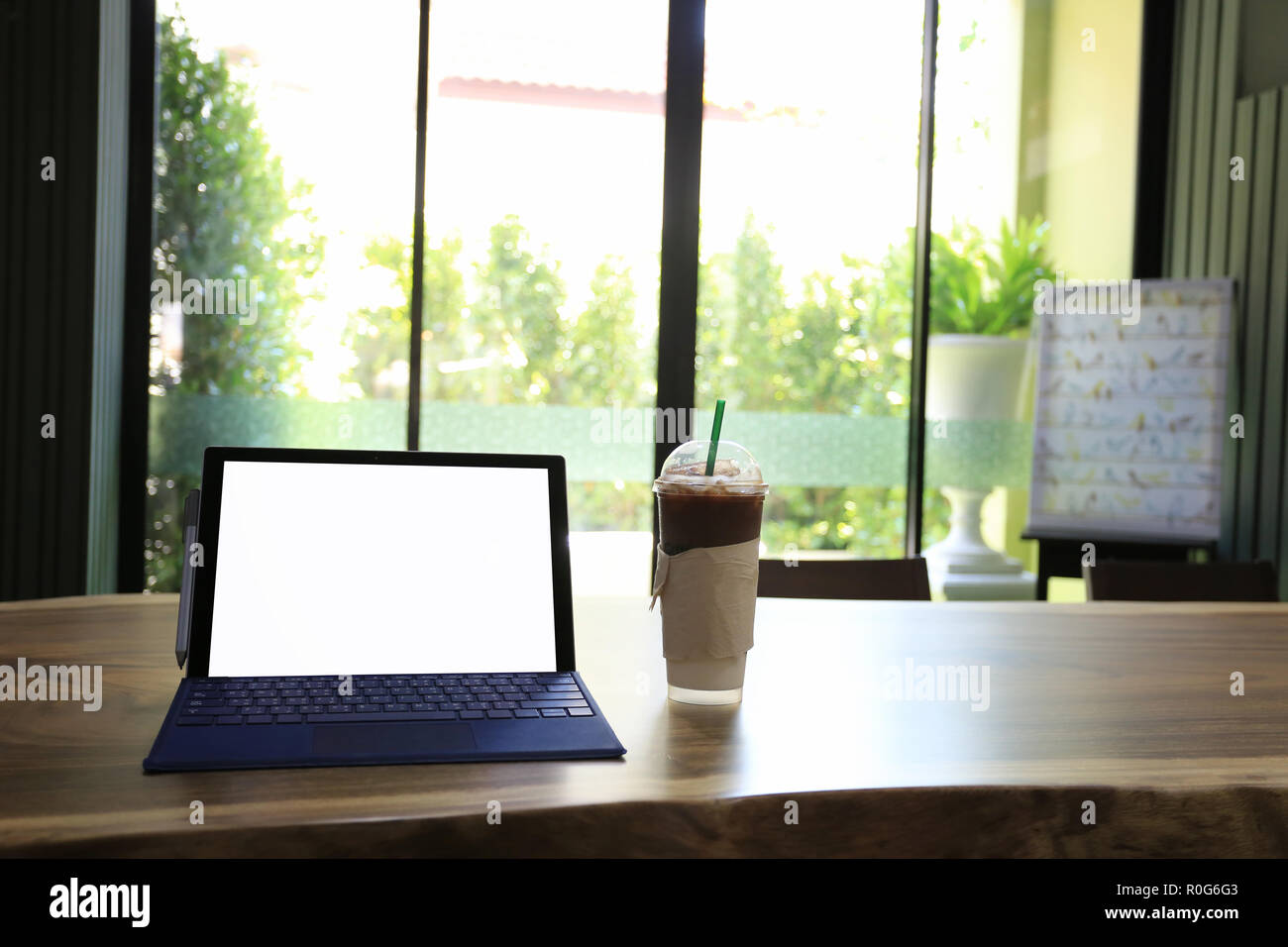 Laptop blank screen of white color placed on a table in a restaurant ...