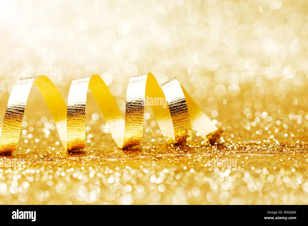 Golden curly ribbon decoration on glitter background close-up Stock ...