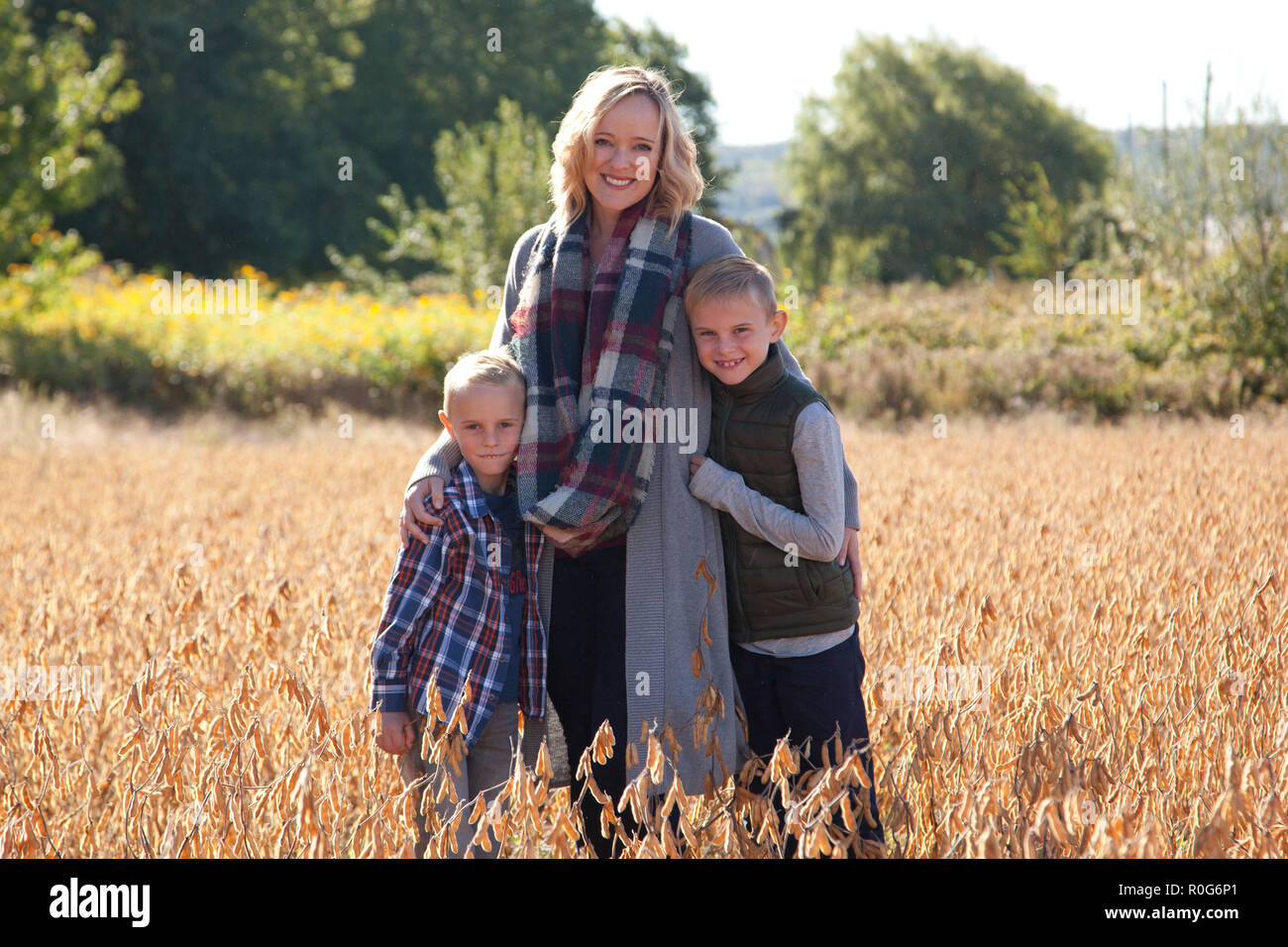 A beautiful smiling mom puts her arms around her two sweet sons ...
