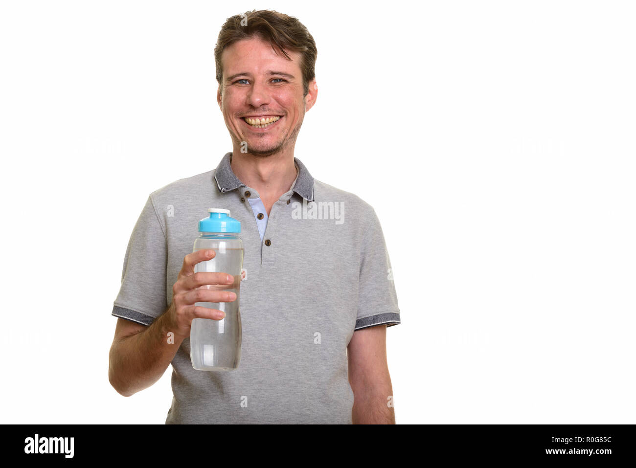 Happy Caucasian man holding water bottle while smiling Stock Photo - Alamy
