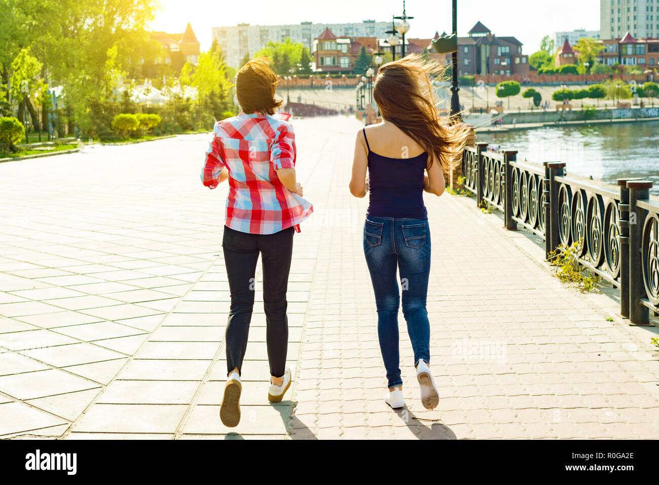 Women running along the road in the park. Urban background, back view ...