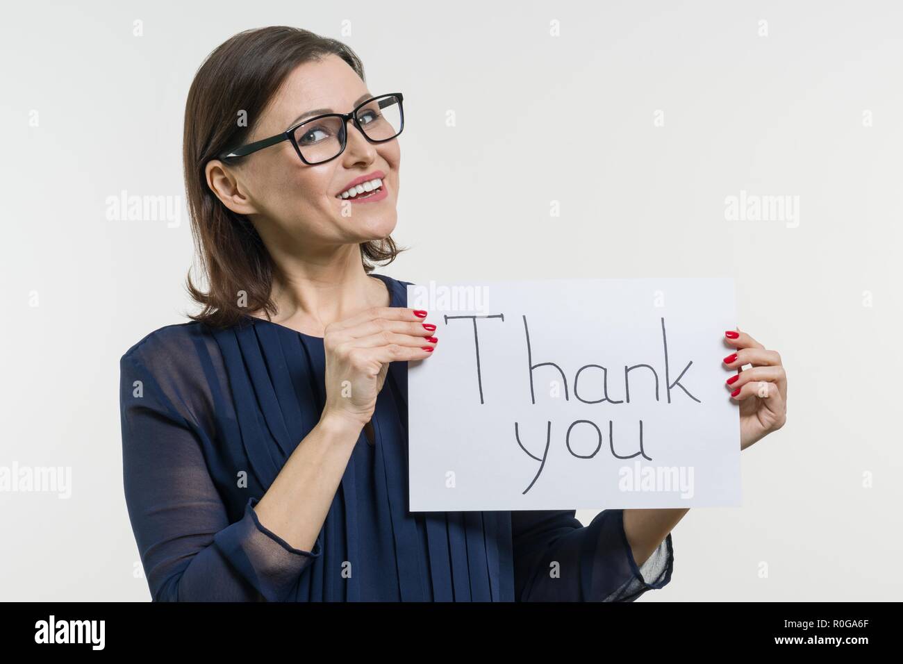 Happy businesswoman showing thanks. Holds the paper with the text thank ...