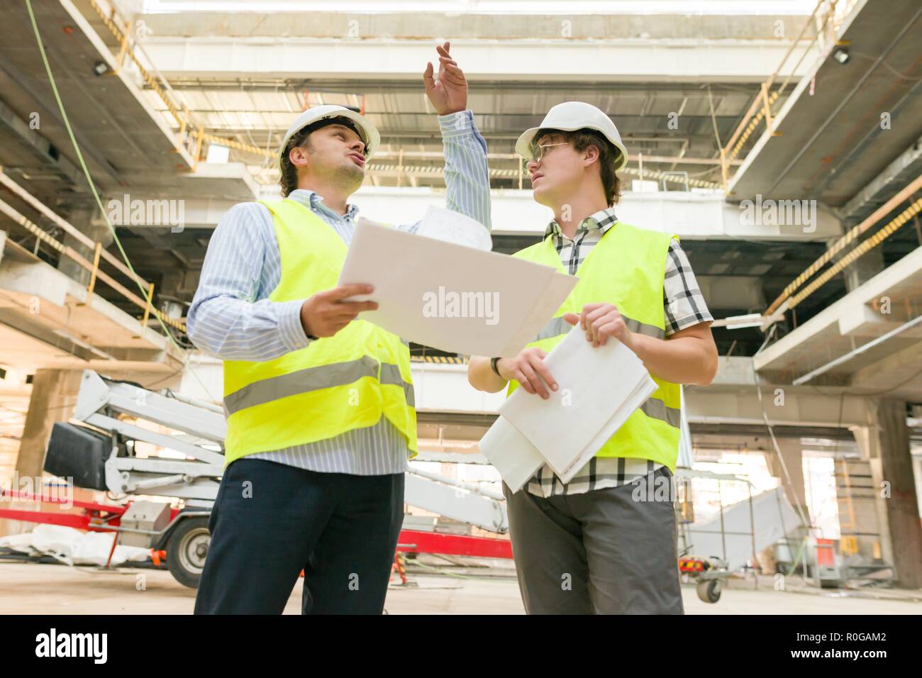 Male construction worker and engineer at the construction site ...
