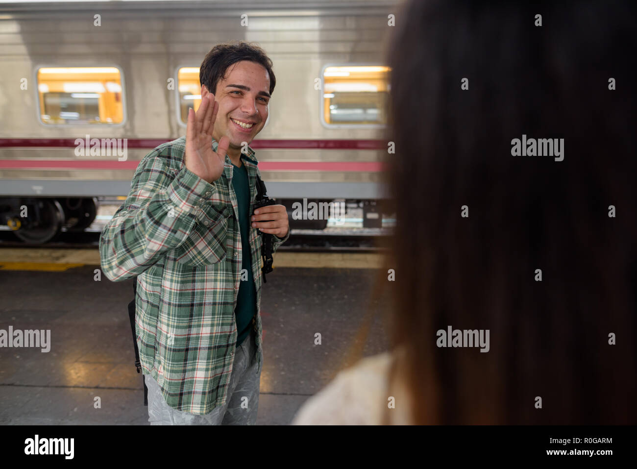 Man waving to young Asian tourist woman in train station Stock Photo ...